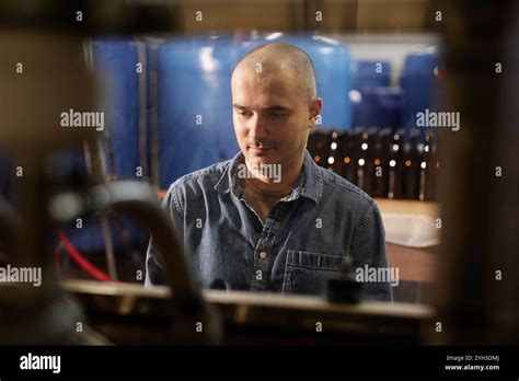 Shot Through Factory Machinery Of Happy Male Production Worker Wearing