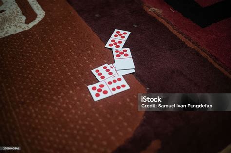 패턴이 있는 카펫 위에 빨간 점 타일을 배치하여 진행 중인 도미노 게임을 클로즈업한 것으로 플레이어의 손과 발 부분이 소프트 포커스로 보입니다 0명에 대한 스톡 사진 및