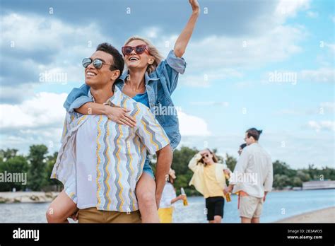 Handsome Bi Racial Man Piggybacking Girlfriend While Walking On Beach