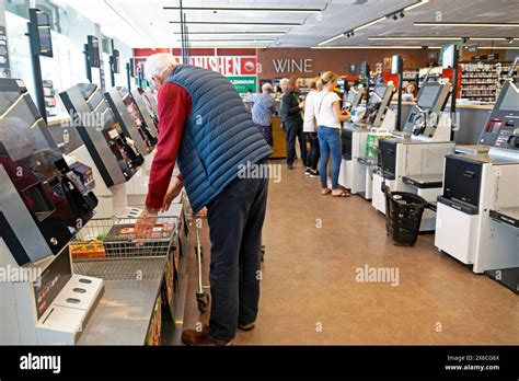 People Customers Shoppers Elderly Older Man Rear Back View Using Self Sevice Checkout Scanners