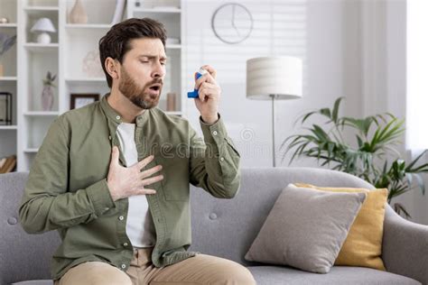 Man Using Asthma Inhaler While Sitting On A Couch At Home Stock Image Image Of Medicine
