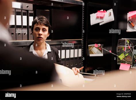 Police Officer Discussing Missing Person Case With Detective Working Overtime At Federal