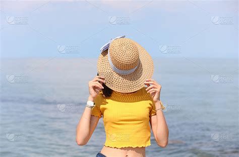 穿着黄色衬衫的女孩戴着一顶宽草帽遮住了脸