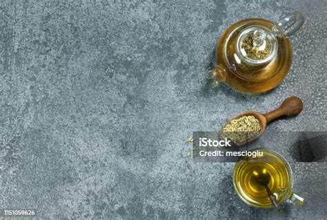 유리 컵에 있는 허브 주입 회 향 차와 회색 소박한 테이블에 나무로 되는 삽에 말린 회 향 씨앗을 가진 유리 차 냄비 0명에