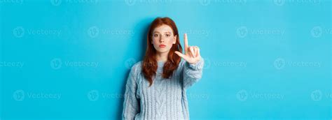 Serious Redhead Girl In Sweater Showing Taboo Gesture Extending One