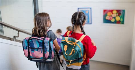 가방을 들고 계단을 내려가는 작은 여고생 친구들의 뒷모습 학교 개념으로 돌아갑니다 사진 Unsplash의 배낭 이미지