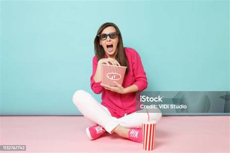 장미 셔츠 밝은 분홍색 파란 파스텔 벽 배경 스튜디오에 고립 된 영화 필름을 보고 바닥에 앉아 흰색 바지에 전체 길이 초상화 재미 있는 여자 패션 라이프 스타일 개념입니다
