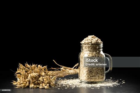 귀리 무리 고 검은 배경에 고립 Flavouring 항아리에 조각 곡물 꽃다발 어두운 나무 테이블에 골든 귀리 Spikelets 말린된 곡물으로 가득 수 있습니다 식품