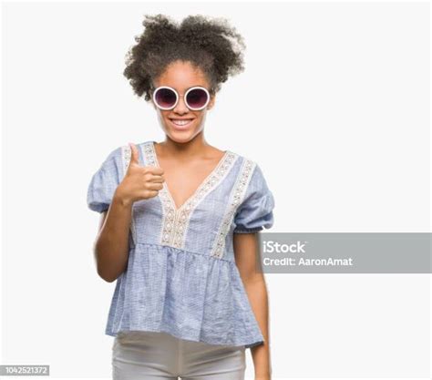 젊은 아프리카 미국 여자 행복 엄지손가락 손으로 제스처를 하 고 격리 된 배경 위에 안경 착용 승인 성공을 보여주는 카메라를 보고 하는 식 긍정적인 감정 표현에 대한 스톡