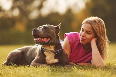 Laying Down On The Ground Woman In Casual Clothes Is With Pit Bull