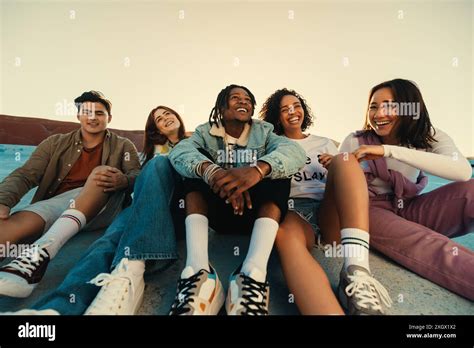 Happy Group Of Friends Sitting Together Outdoors Smiling And Laughing