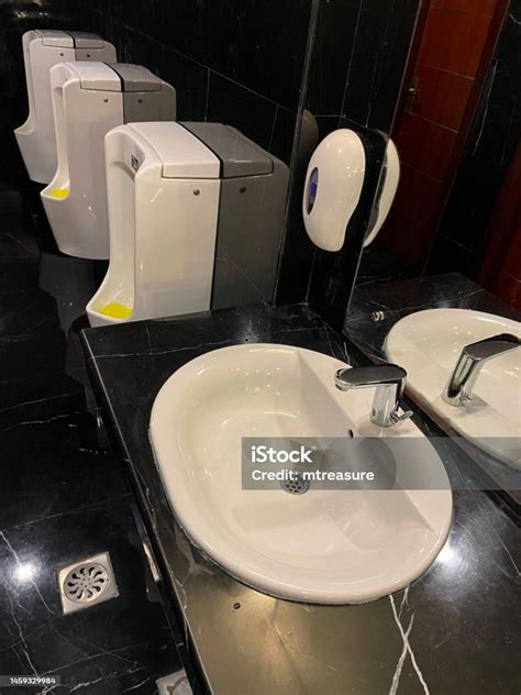 공공 호텔 욕실 검은 대리석 벽과 바닥 마호가니 문 배경에 소변기에 금속 수도꼭지와 플러그 구멍이 있는 백자 싱크대 이미지 0명에 대한 스톡 사진 및 기타 이미지 Istock