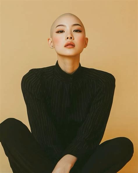 A Bald Asian Girl Sits On The Floor On Beige Background