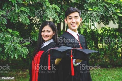 검은 색 졸업 가운을 입은 남녀 부부 또는 졸업 모자를 쓰고 축하하는 졸업생이 공원 배경으로 서서 미소를 지으며 모자를 들고