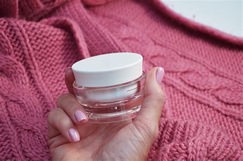 로션이 든 흰색 항아리 부드럽고 따뜻한 밝은 분홍색 스카프 스웨터의 배경에 아름다운 손톱이 있는 여성 손에 보습제 전문 매니큐어 화장품 모형 가을에 대한 스톡 사진 및 기타