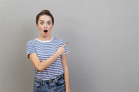 놀란 표정으로 카메라를 바라보는 여자가 복사 공간을 가리킨다 25 29세에 대한 스톡 사진 및 기타 이미지 25 29세 겨냥 경외감 Istock