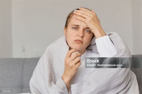 아픈 여성이 담요에 싸여 앉아 이마에 손을 대고 부정적인 감정을 표현하고 나쁜 느낌 치료가 필요하고 얼굴을 찡그린 얼굴 두통 및