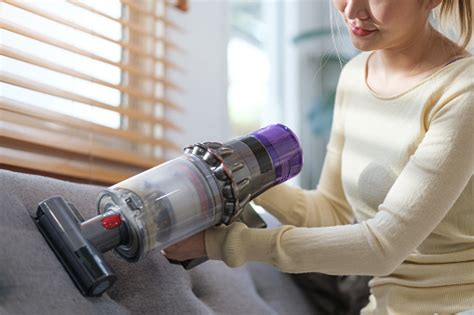 젊은 주부는 무선 진공 청소기로 소파에서 먼지와 흙을 진공 청소기로 청소합니다 가정 위생 및 기술 개념입니다 20 24세에 대한 스톡 사진 및 기타 이미지 Istock