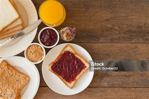 오렌지 주스와 토스트 빵 집에서 만든 딸기 잼 땅콩 버터와 함께 제공 됩니다 아침 식사 테이블에 땅콩 버터와 잼의 수 제 토스트 빵 상위 뷰 평면에 맛 있는 토스트 빵이