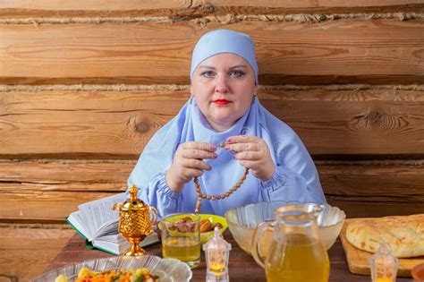 A Muslim Woman In A Blue Hijab Is Fingering Her Rosary At The Iftar Ramadan Table Stock Photo