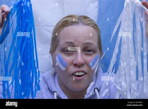 Blonde Woman With A Flag And Face Painted In The Colors Of Argentina