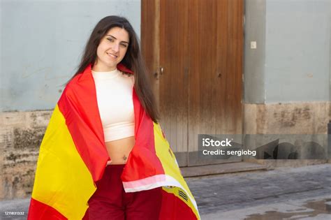 스페인 국기 스페인 셀카 도시에서 흰색 상단과 빨간 바지 어두운 공기를 들고 행복 한 매력적인 젊은 여성 모델의 초상화 복사 공간에 텍스트를 배치합니다 거리에 대한 스톡