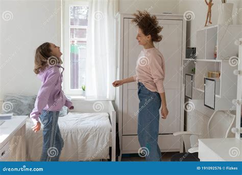 Happy Teenage Daughter And Mother Having Fun Dancing At Home Stock