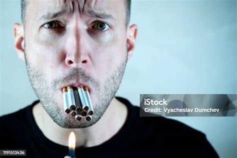 고통받는 얼굴을 가진 남자는 그의 입에 담배를 많이 들고 카메라를 보고 공간을 복사 거친에 대한 스톡 사진 및 기타 이미지