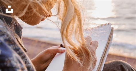 파란색과 흰색 꽃무늬 셔츠를 입은 여자가 낮 동안 물가 근처에서 책을 들고 있다 사진 Unsplash의 무료 웰빙 이미지