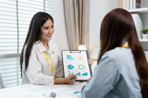 Business Meeting With Two Women Discussing Charts And Graphs In A