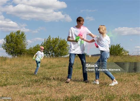 백인 가족은 생일 파티에서 화려한 염료를 가지고 놀거나 홀리 컬러 페스티벌을 축하하며 여러 가지 빛깔의 가루를 던집니다 쾌활한 부모 아이는 공원에서 야외에서 페인트를 가지고
