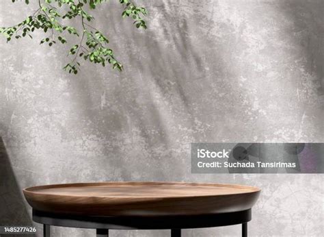 현대적이고 미니멀한 티크 나무 둥근 부드러운 곡물 연단 테이블 검은 강철 다리 햇빛에 녹색 열대 나무 빈 콘크리트 벽에 잎