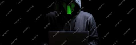 Premium Ai Image Hacker Without Face In A Hood Holds A Laptop On A