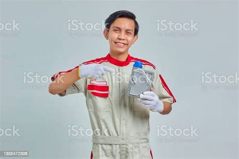 회색 배경 위에 엔진 오일 플라스틱 병을 보여주는 정비공 유니폼을 입고 쾌활한 잘 생긴 남자의 초상화 30 34세에 대한 스톡