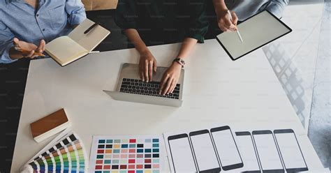 그래픽 디자인 팀이 함께 작업하고 스마트폰의 새로운 기능에 대해 브레인스토밍하는 상위 뷰 이미지입니다 협업공동 작업자회의