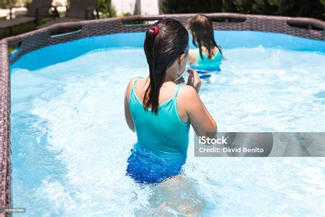 수영장에서 등을 돌린 두 소녀가 물속에서 즐거운 시간을 보내고 있습니다 수영장 수영 수영복 어린이 여름 휴식 휴가 리조트 및 여행 개념 2명에 대한 스톡 사진 및 기타