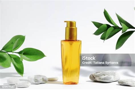 자외선 차단 태닝 또는 모발을 위한 노란색 오렌지 오일 병을 클리어합니다 하드 그림자 식물과 돌 흰색 배경 여름 케어 화장품