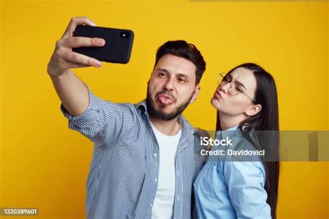 재미있는 부부는 얼굴을 찡그린다 노란색 벽을 통해 스마트 폰에 셀카를 소요 가족에 대한 스톡 사진 및 기타 이미지 가족 셀카 스마트폰 Istock