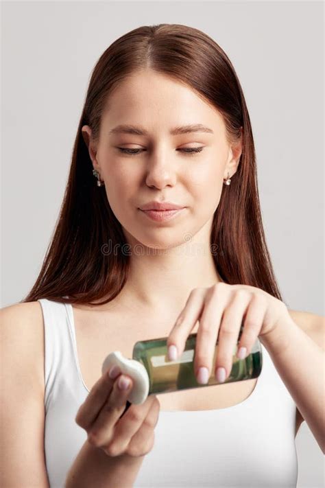 Young Lovely Long Haired Girl Applying Cleansing Lotion To A Cotton Pad