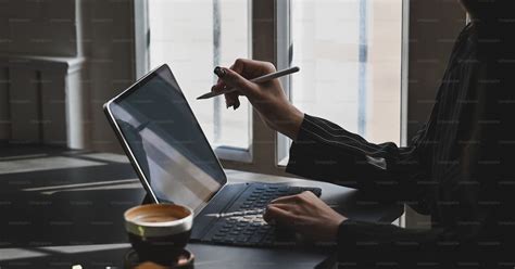 젊은 임원 여성은 고급 사무실을 배경으로 현대적인 작업 책상에서 일하는 것에 대해 생각하면서 컴퓨터 태블릿에 전기 펜을 가리키고 있습니다 사진 Unsplash의 테이블 이미지