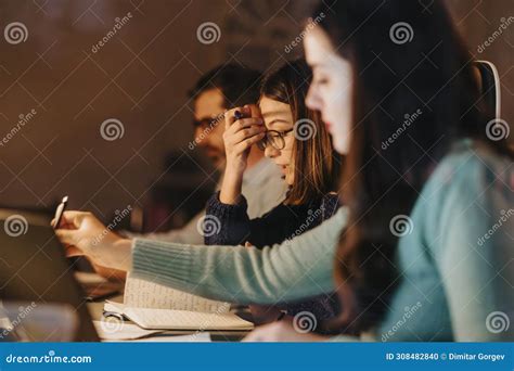 Three Focused Colleagues Working Together On A Project In A Dimly Lit
