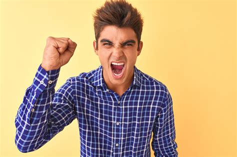 고립 된 노란색 배경 에 서 캐주얼 셔츠를 입고 젊은 잘 생긴 남자는 분노와 함께 외치는 동안 좌절과 분노를 제기 주먹 분노와 공격적인 개념 감정에 대한 스톡 사진 및 기타
