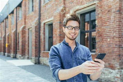 Retrato De Jovem Estudante Do Sexo Masculino Fora Do Campus Segurando O Celular Sorrindo E