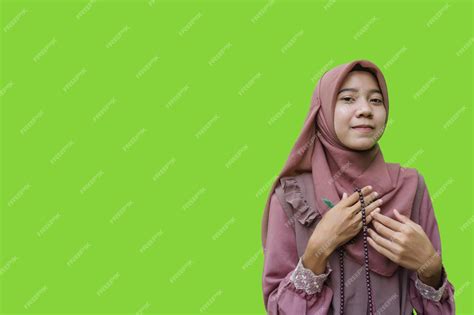 녹색 배경을 가진 그녀의 손에 기도 구슬을 들고 아름다운 아시아 이슬람 여성 히잡 프리미엄 사진