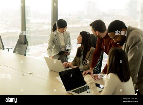 A Diverse Group Of Professionals Collaborates Around A Table In A Sleek Office Sharing Ideas