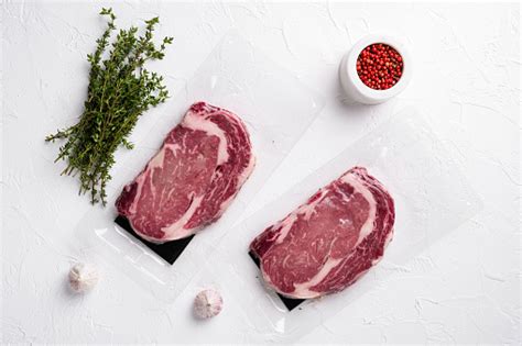 신선한 쇠고기 스테이크와 진공 플라스틱 팩 흰색 돌 테이블 배경에 상단 보기 플랫 레이 Entrecôte에 대한 스톡 사진 및