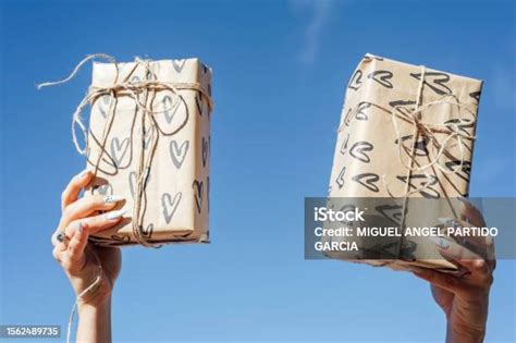 푸른 하늘 위에 두 개의 공예 종이 선물 상자를 들고 있는 여성의 손의 1인칭 평면도 사진 고름에 대한 스톡 사진 및 기타 이미지 고름 공예 공휴일 Istock
