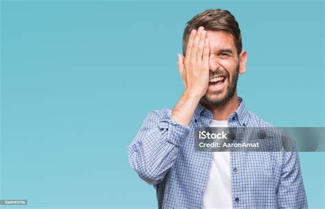 잘생긴 젊은이 얼굴과 놀라운 감정에 확신 미소와 함께 손으로 한쪽 눈을 덮고 격리 된 배경 위에 흰색 T셔츠를 입고 T 셔츠에 대한 스톡 사진 및 기타 이미지 Istock