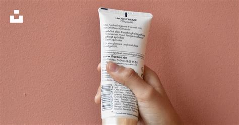 분홍색 벽에 자외선 차단제 튜브를 들고 있는 손 사진 Unsplash의 무료 로션 이미지