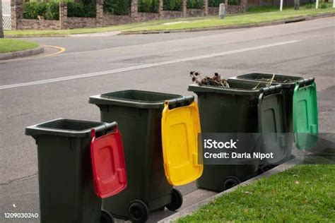 가정용 쓰레기와 녹색 정원 폐기물을 재활용하기위한 다채로운 뚜껑이있는 호주 쓰레기 바퀴 달린 쓰레기통이 거리 연석에 줄지어 서서